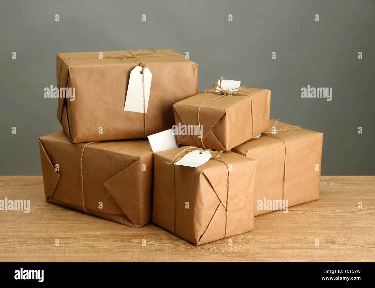 parcels boxes with kraft paper, on wooden table on grey background ...