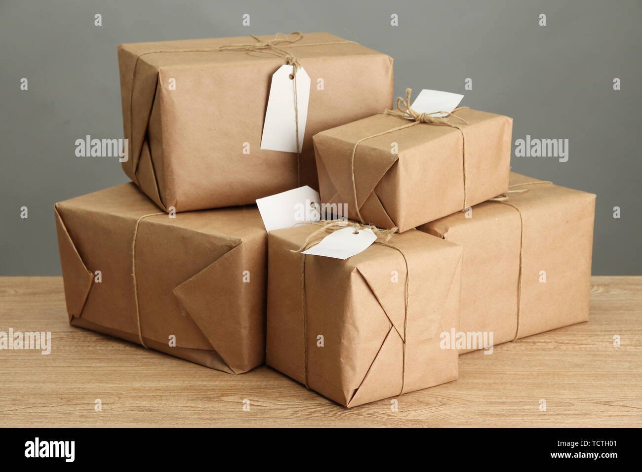 parcels boxes with kraft paper, on wooden table on grey background ...