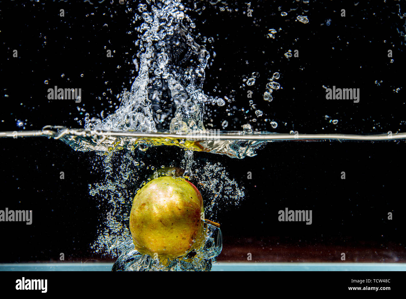 apple falling in dark water with splashes in the air Stock Photo - Alamy