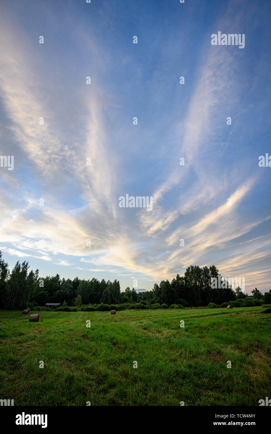 dramatic dark red clouds in sunset over countryside fields and forests ...