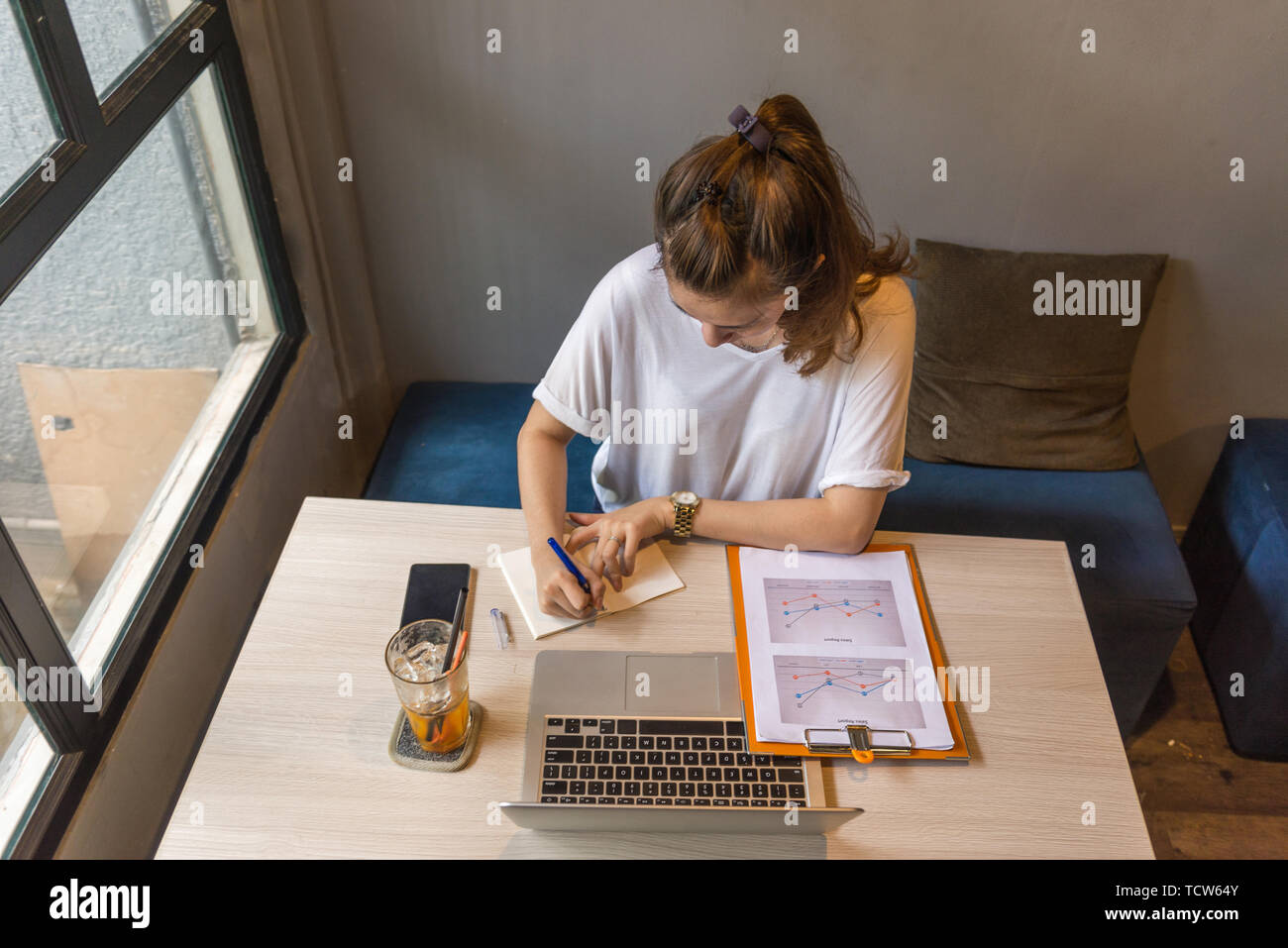 Asian woman writing notes and financial chart report Stock Photo - Alamy