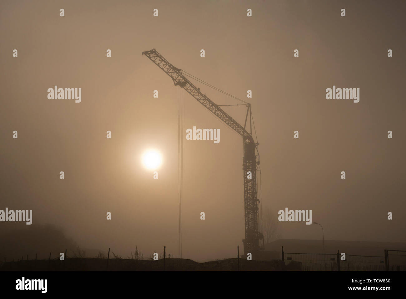 construction tower and sun behind fog Stock Photo - Alamy