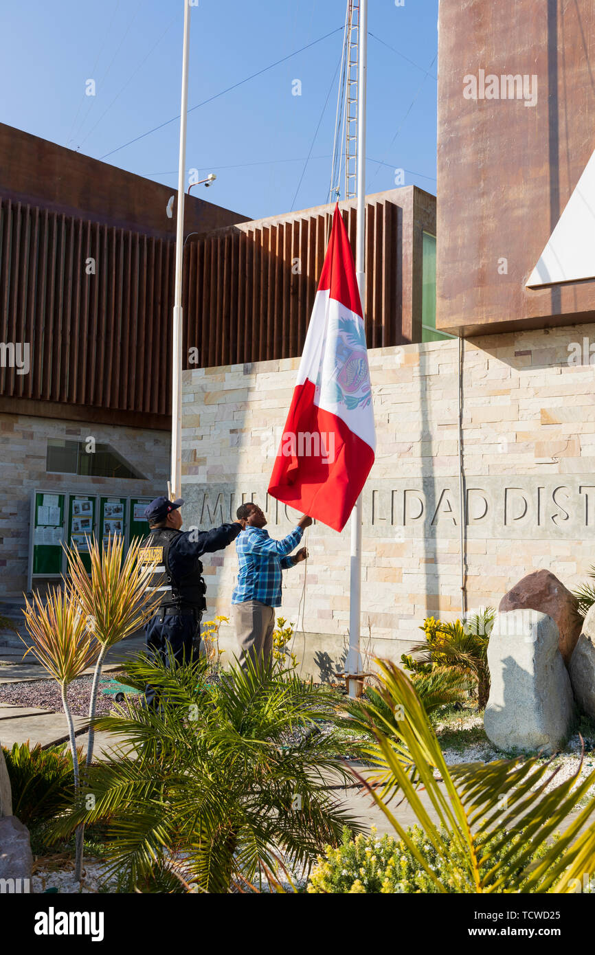 Flag raising outside municipal offices in Paracas, Peru, South America ...