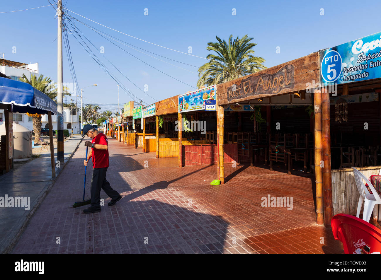 Early morning street sweeper by a row of shack restaurants in Paracas ...