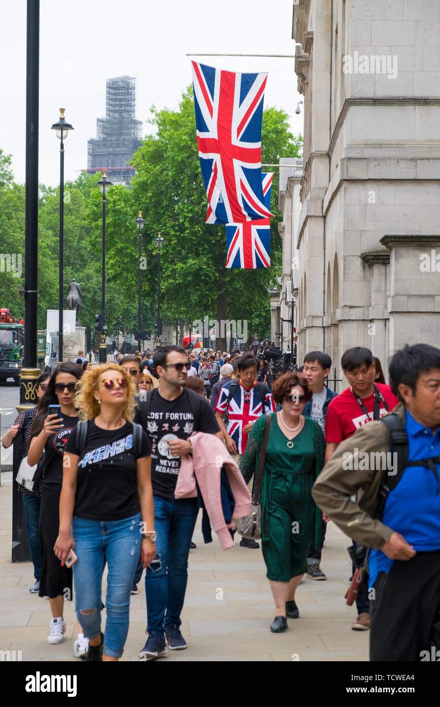Crowds of tourists walk down whitehall below the union jack flags ...