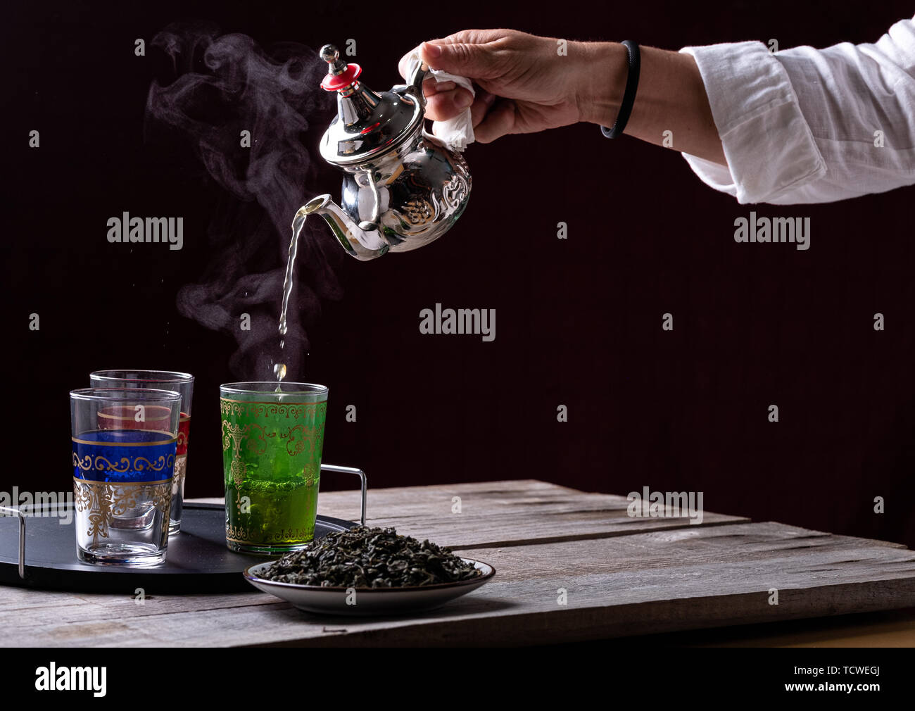 person serving tea in a silver teapot over glass cups Stock Photo - Alamy