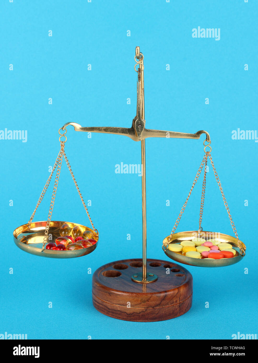 Classic scales with color pills on color background Stock Photo - Alamy