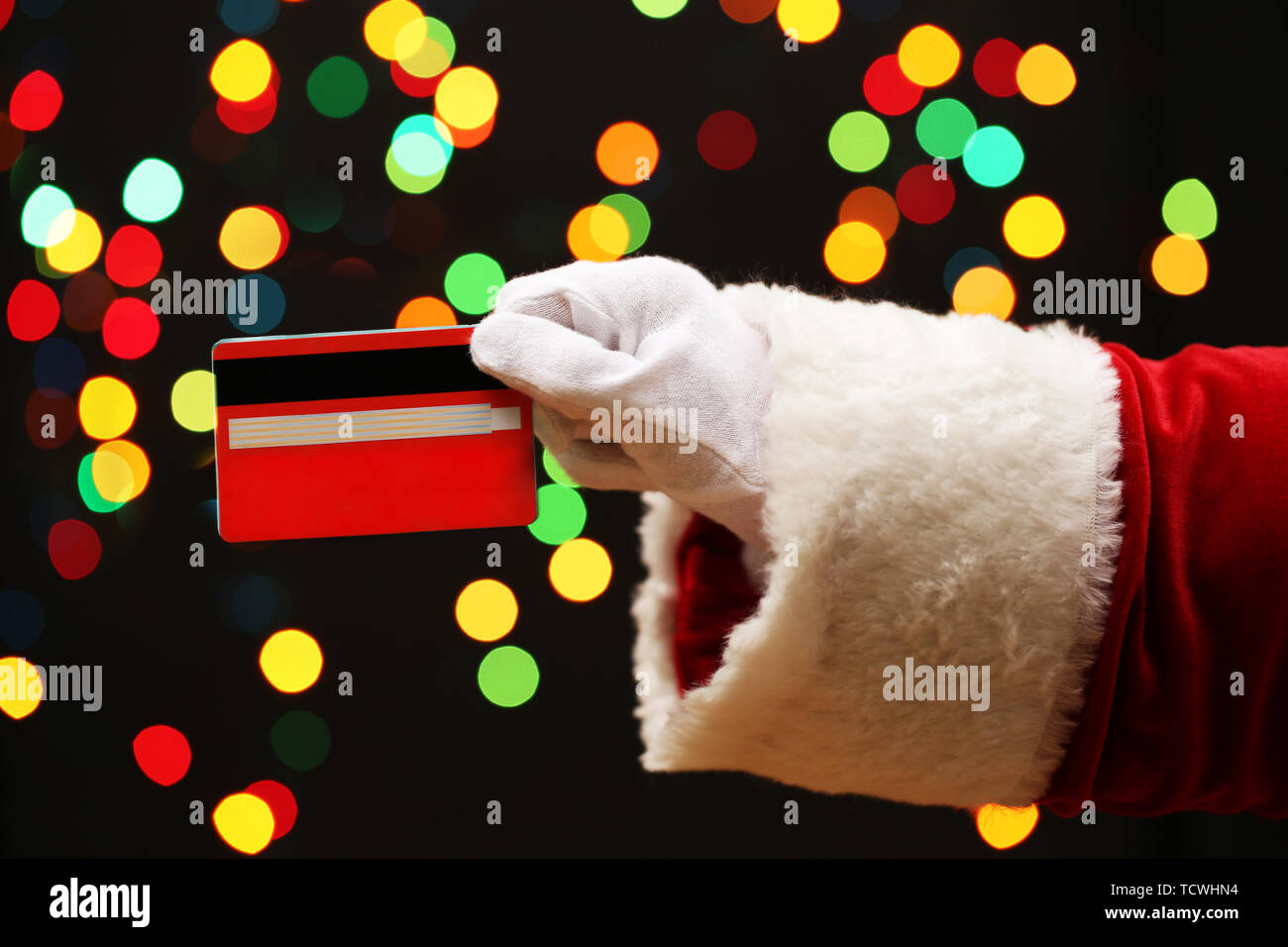 Santa Claus hand holding credit card, on garland background Stock Photo ...