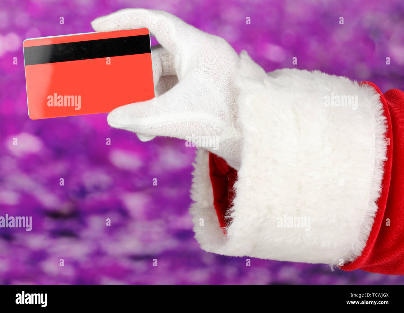 Santa Claus hand holding red credit card on purple background Stock ...