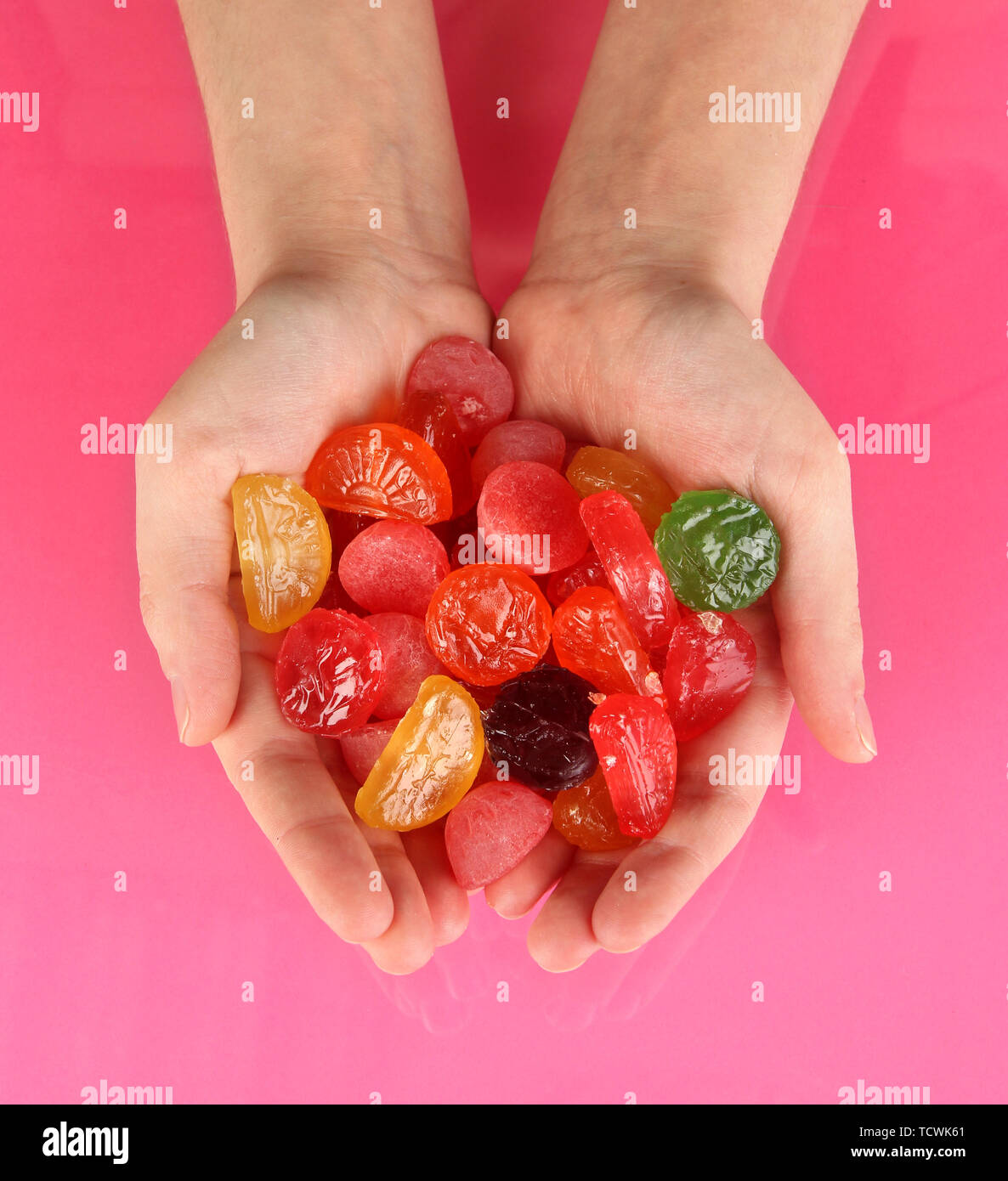 Hands full of sweets on pink background Stock Photo - Alamy