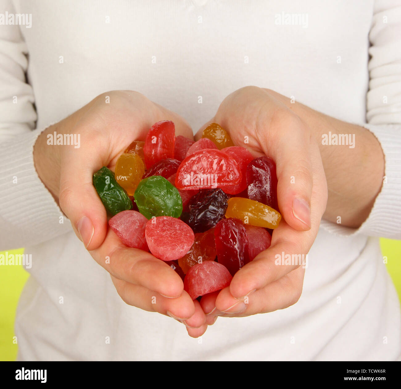 Hands full of sweets on green background Stock Photo - Alamy
