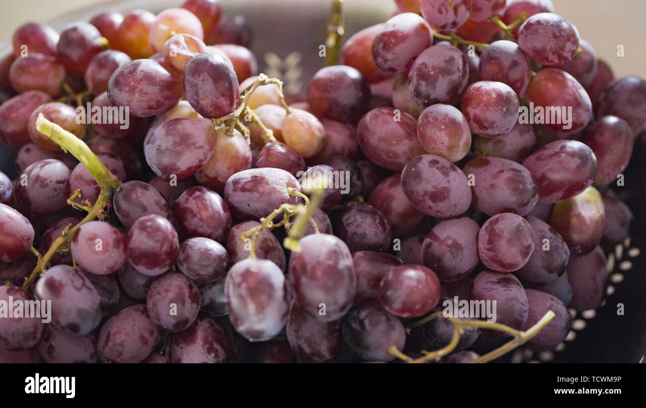 Washing red seedless grapes in stainless steel colander Stock Photo - Alamy