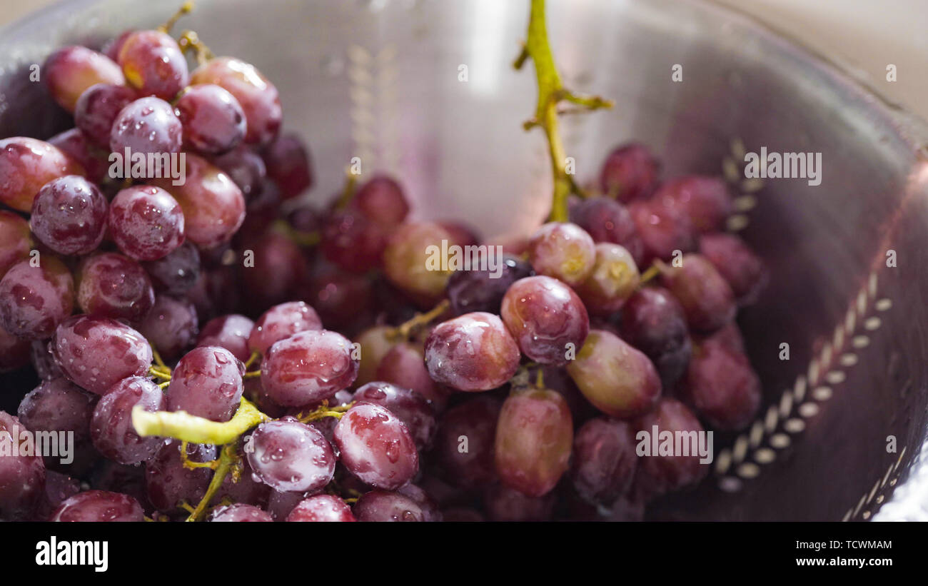 Washing red seedless grapes in stainless steel colander Stock Photo - Alamy