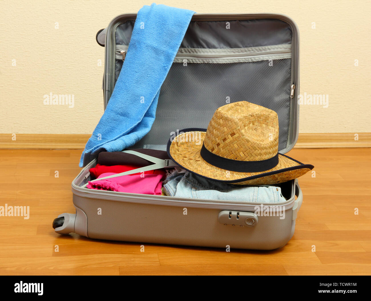 Open silver suitcase with clothing in room Stock Photo - Alamy