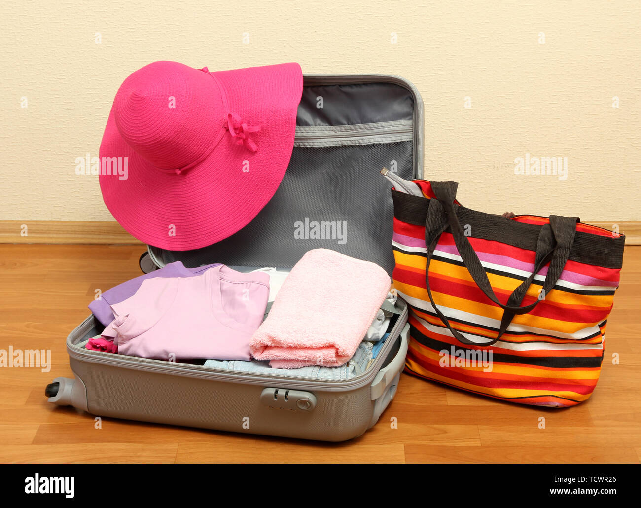 Open silver suitcase with clothing in room Stock Photo - Alamy