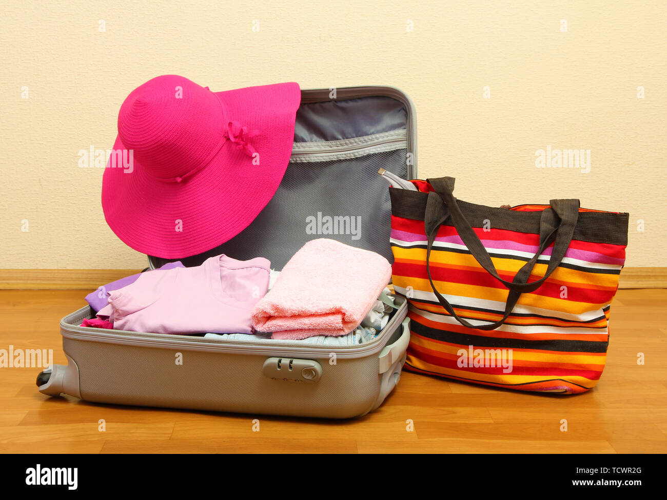 Open silver suitcase with clothing in room Stock Photo - Alamy