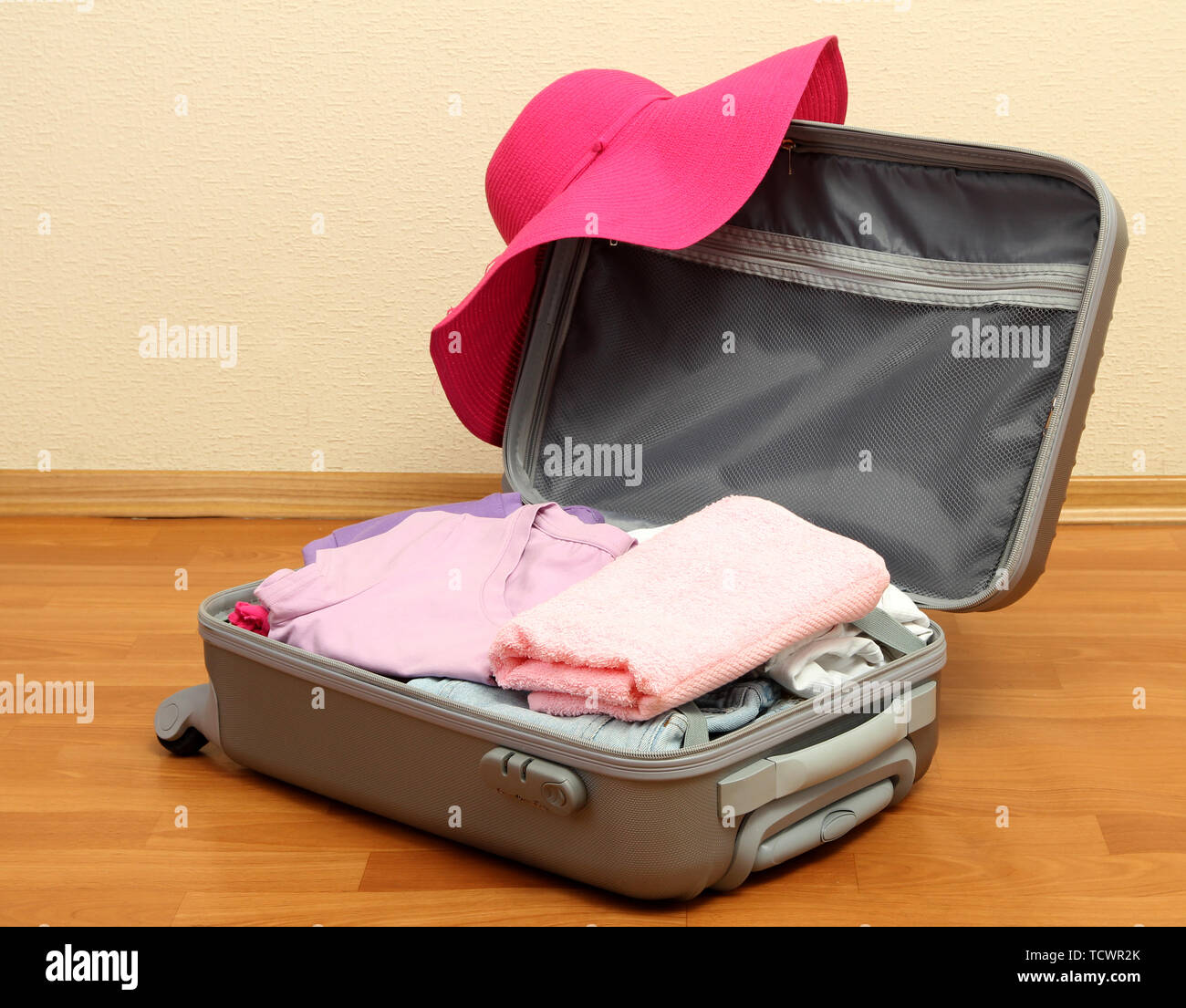 Open silver suitcase with clothing in room Stock Photo - Alamy