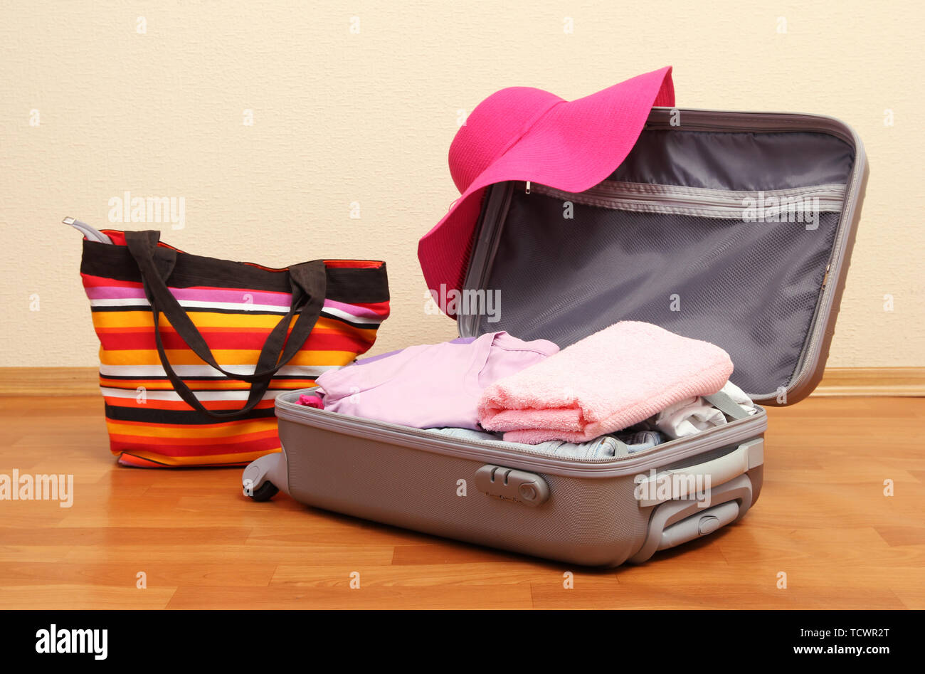 Open silver suitcase with clothing in room Stock Photo - Alamy