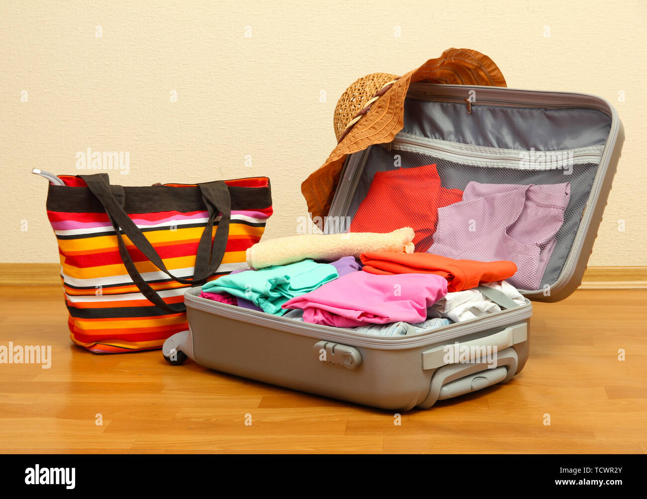 Open silver suitcase with clothing in room Stock Photo - Alamy