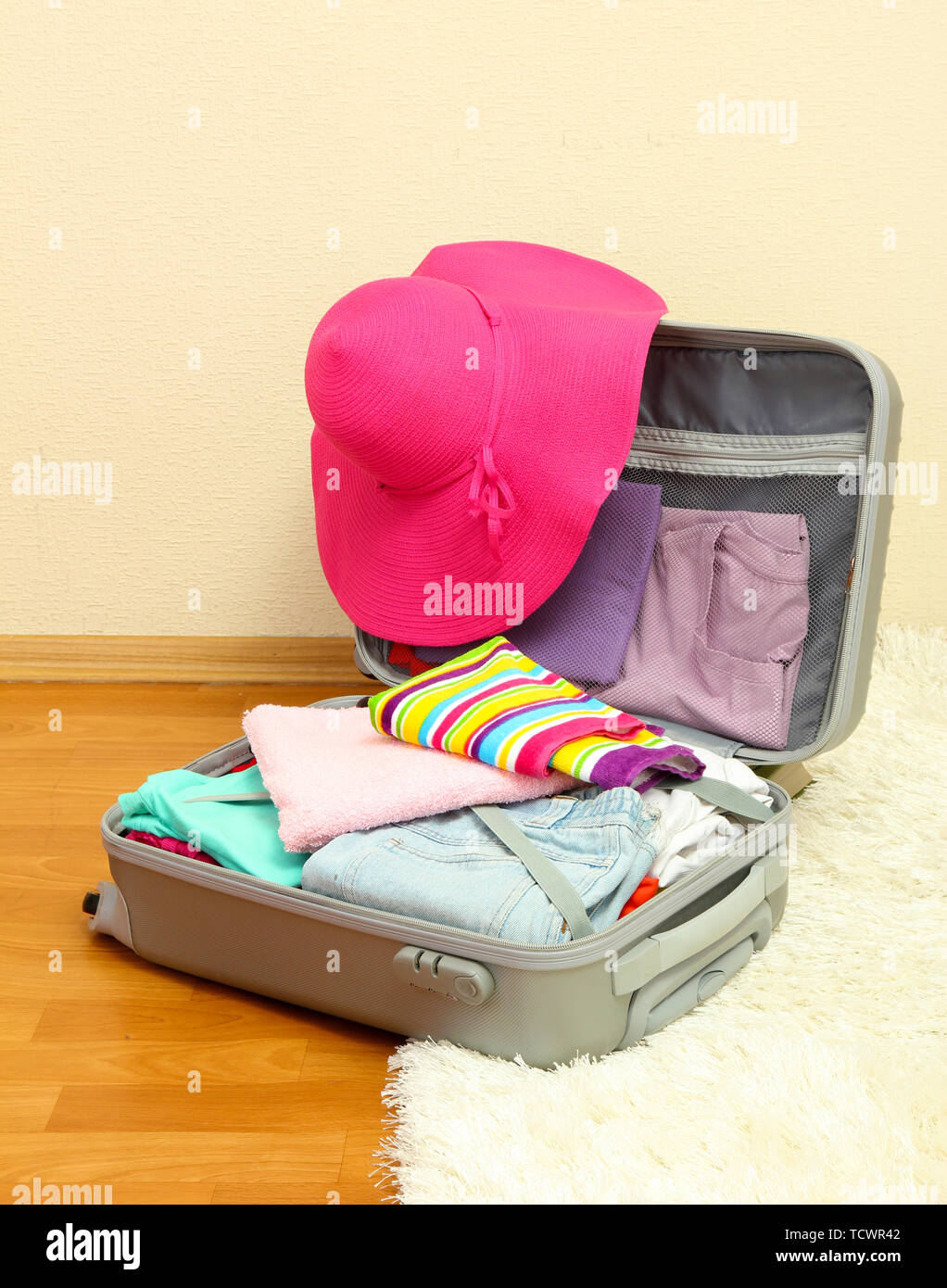 Open silver suitcase with clothing in room Stock Photo - Alamy