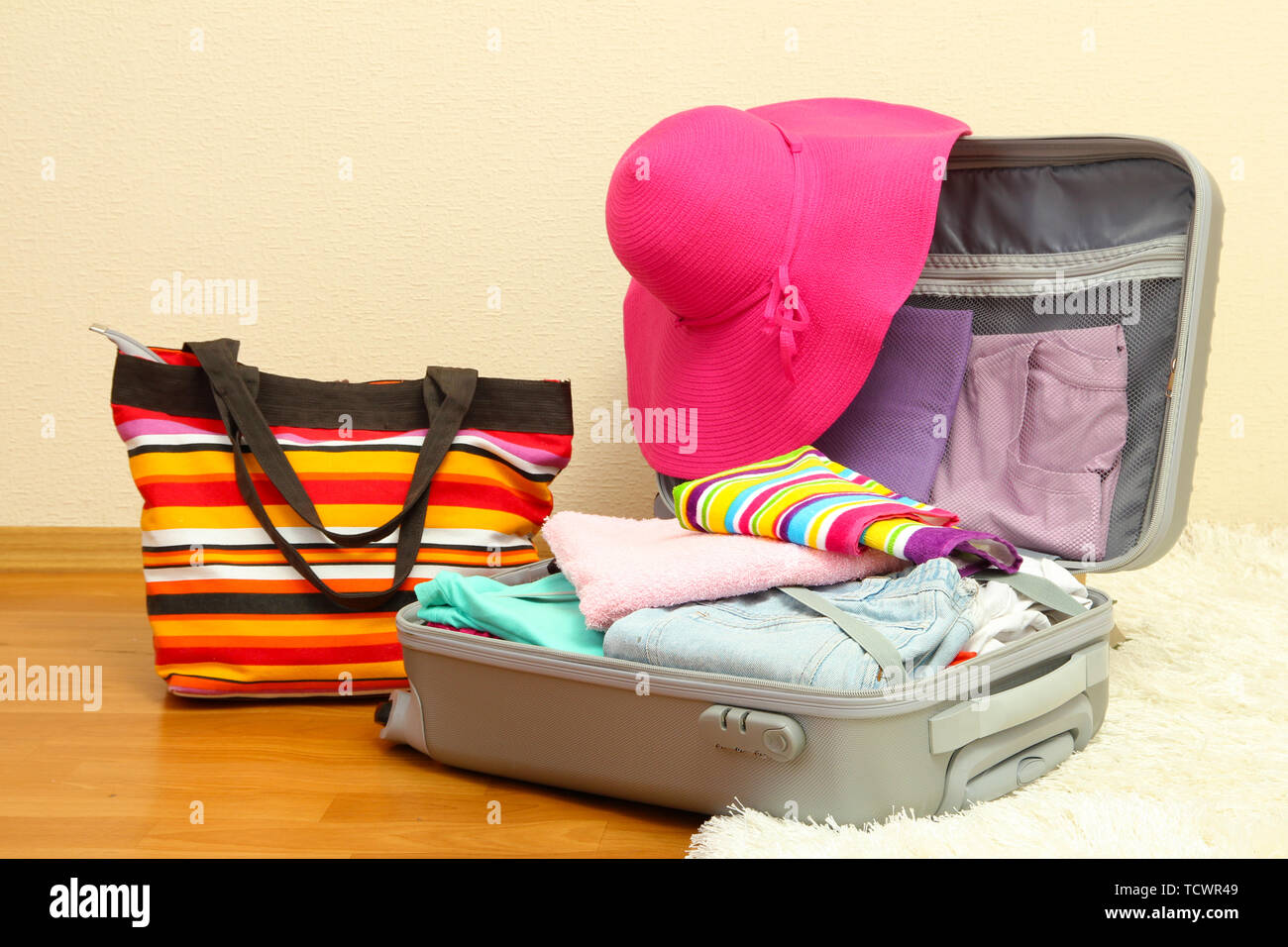 Open silver suitcase with clothing in room Stock Photo - Alamy