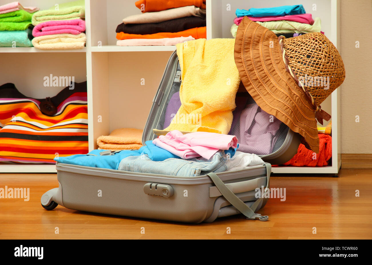 Open silver suitcase with clothing in room Stock Photo - Alamy