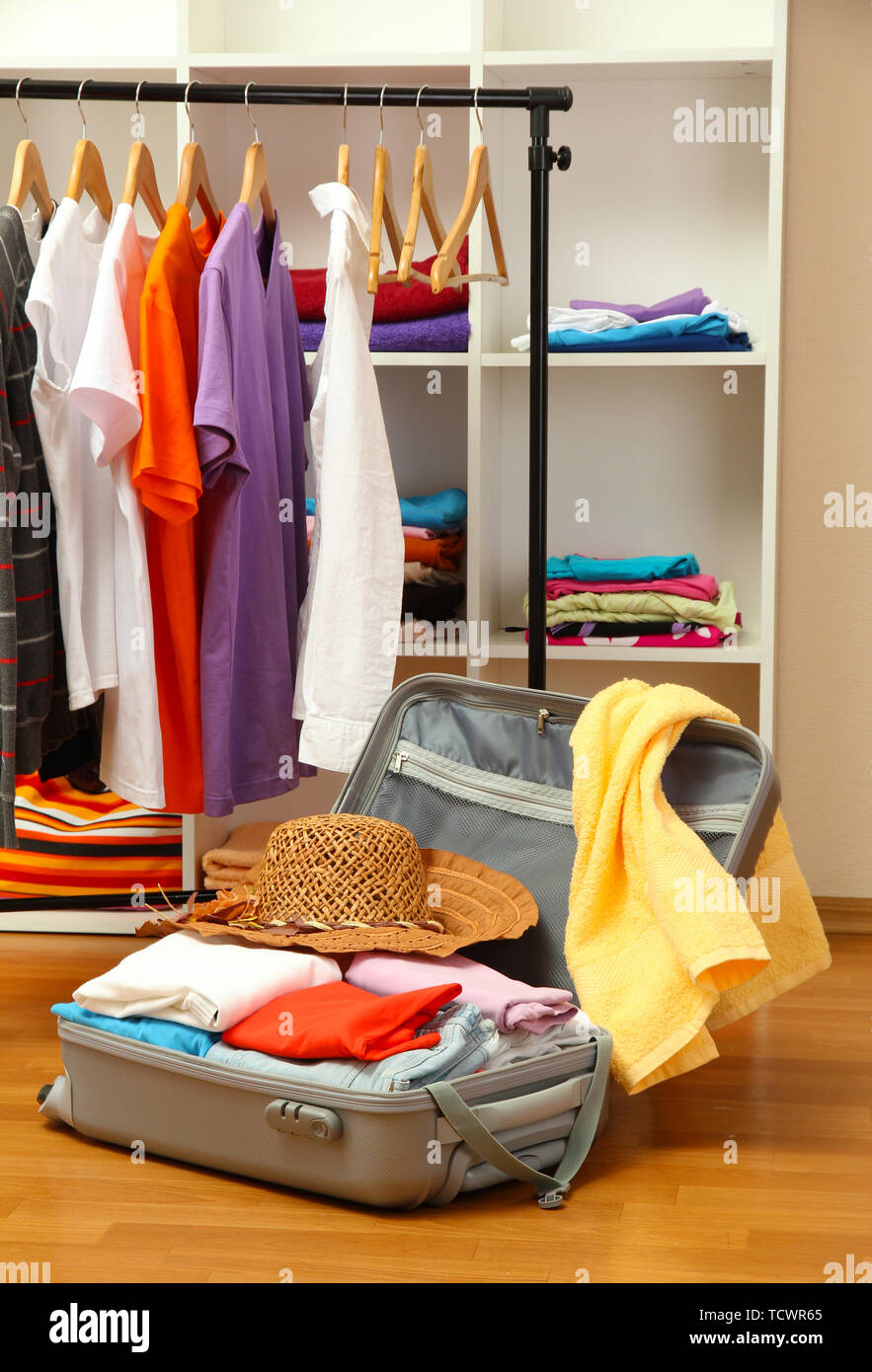Open silver suitcase with clothing in room Stock Photo - Alamy