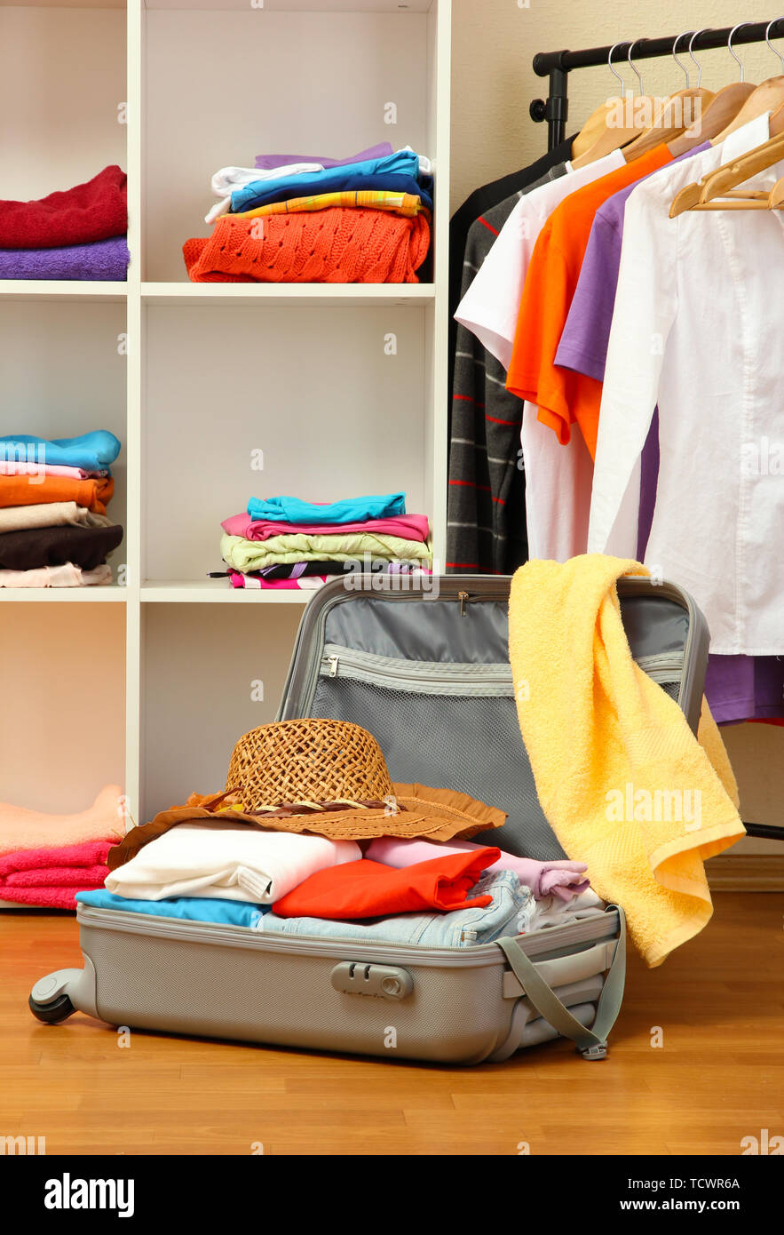 Open silver suitcase with clothing in room Stock Photo - Alamy