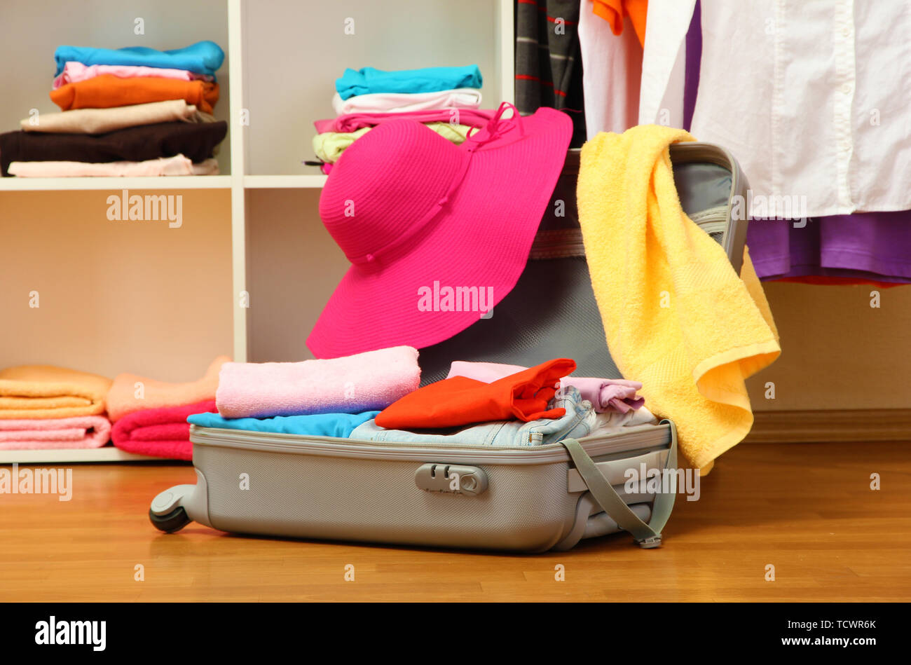 Open silver suitcase with clothing in room Stock Photo - Alamy