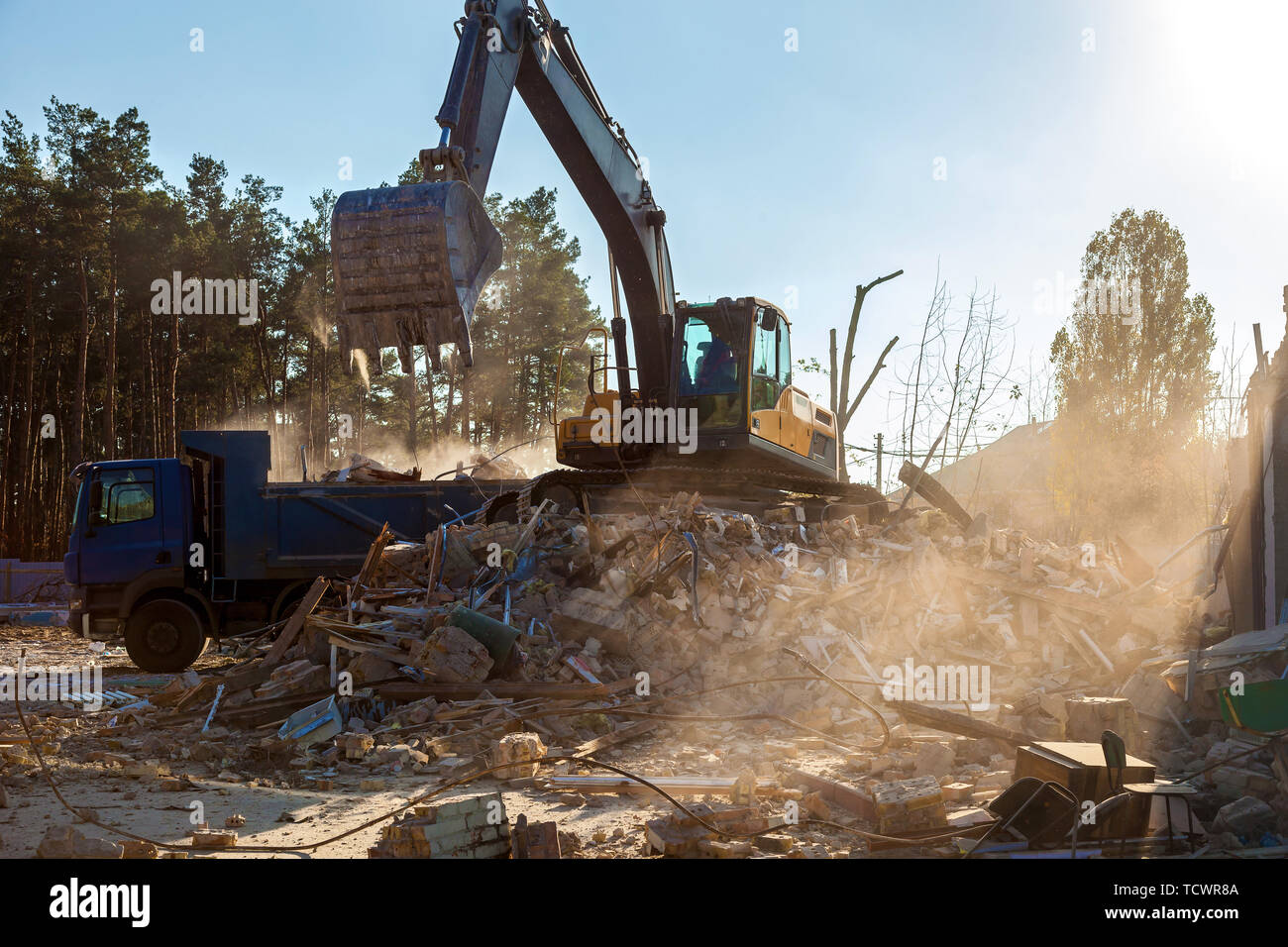 The excavator loads the remains of the destroyed building in the car ...