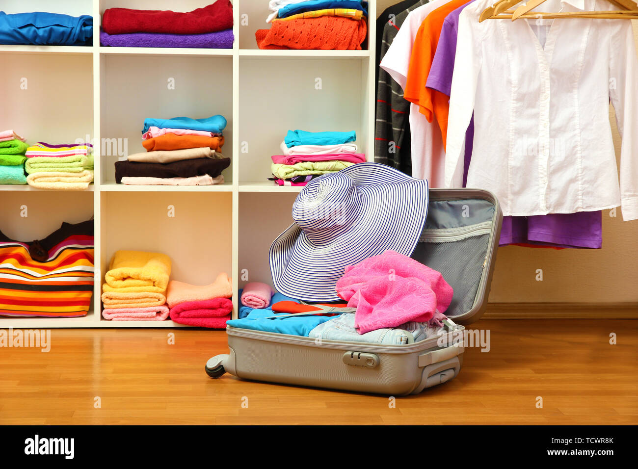 Open silver suitcase with clothing in room Stock Photo - Alamy
