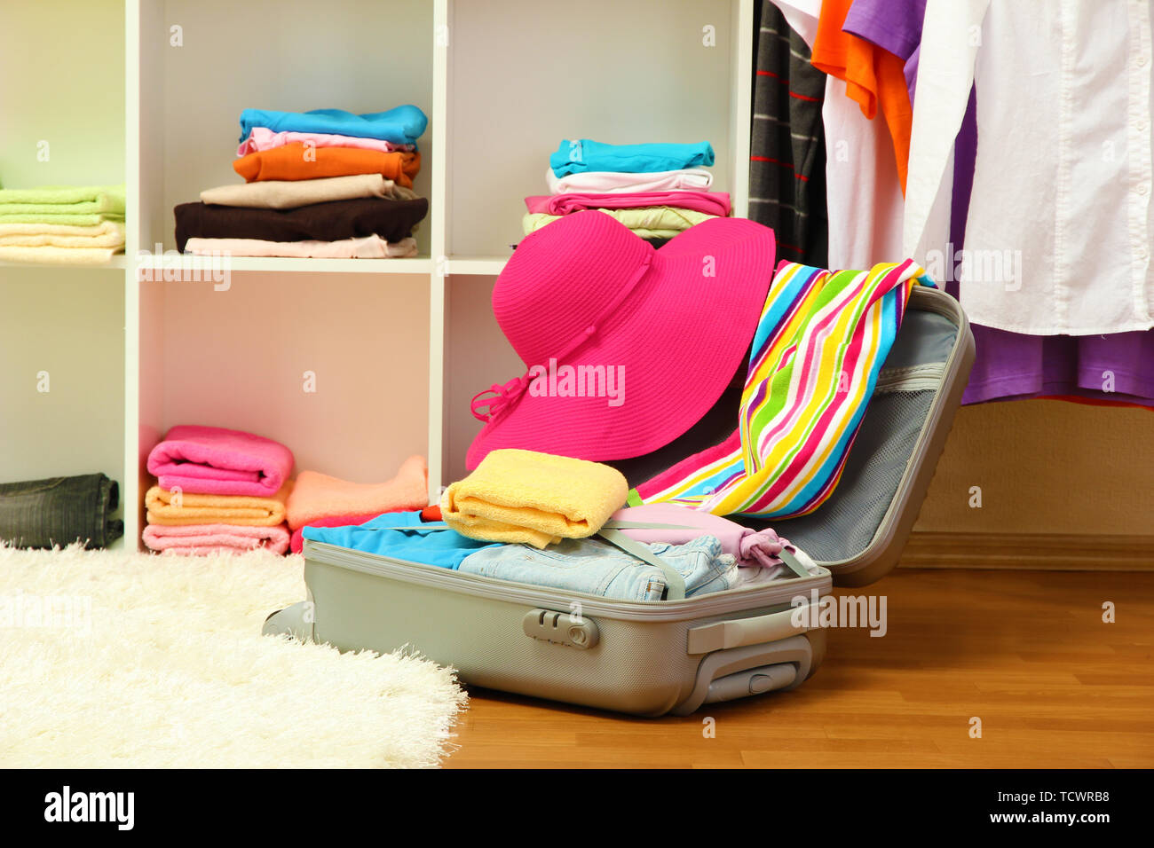 Open silver suitcase with clothing in room Stock Photo - Alamy