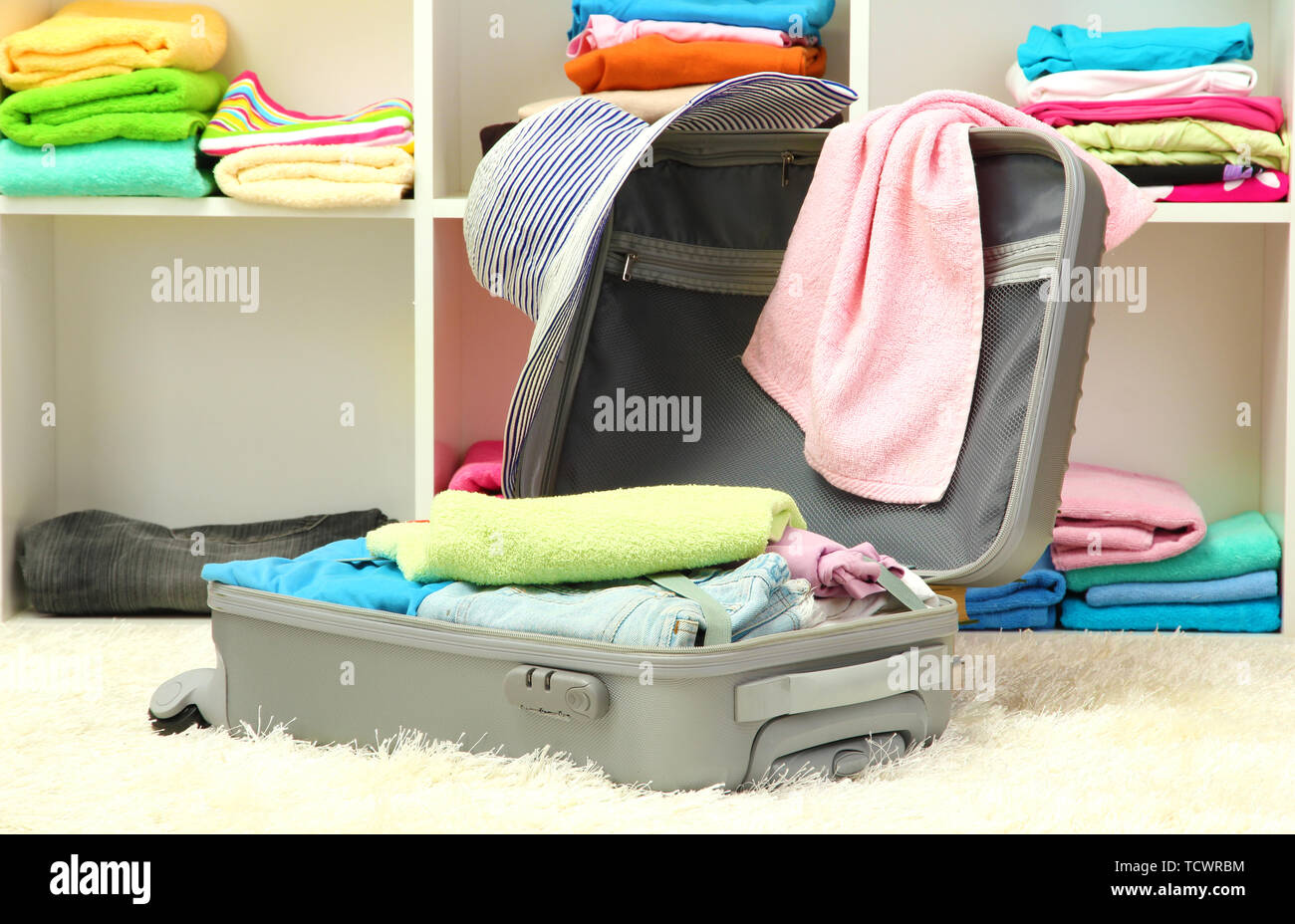 Open silver suitcase with clothing in room Stock Photo - Alamy