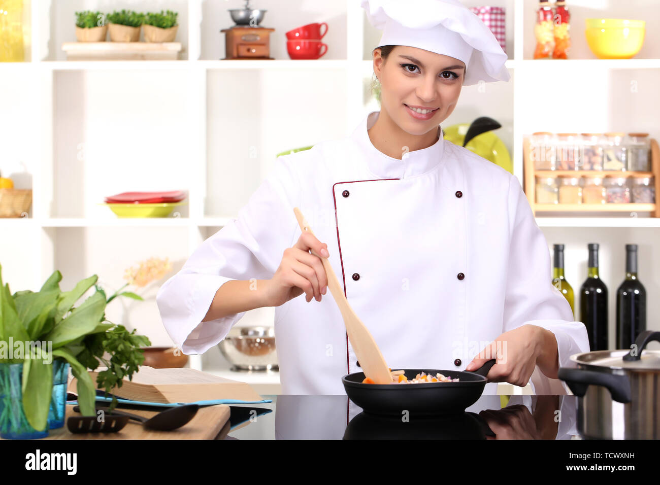 Young woman chef cooking in kitchen Stock Photo - Alamy