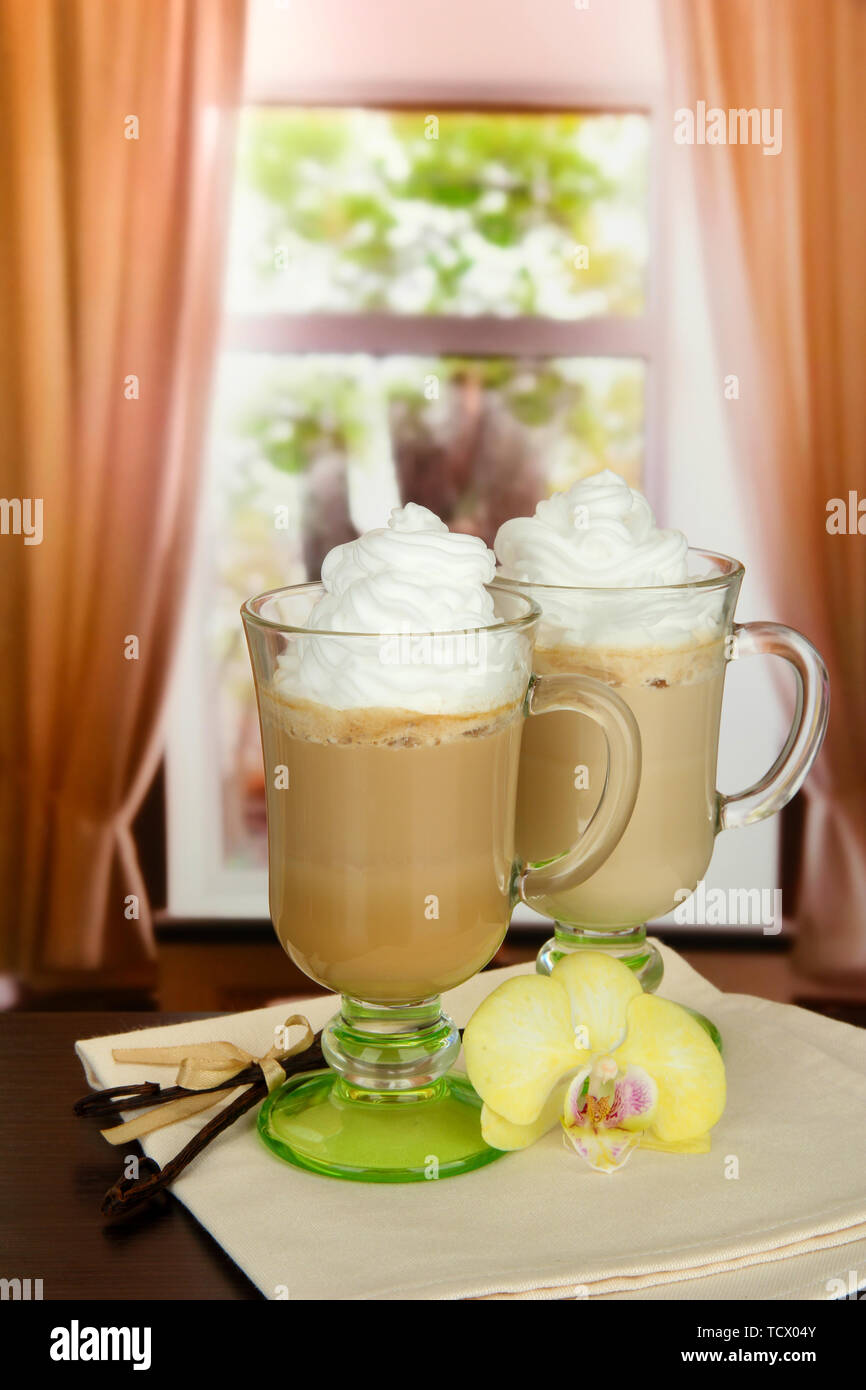 Fragrant coffee latte in glasses cups with vanilla pods, on table in ...