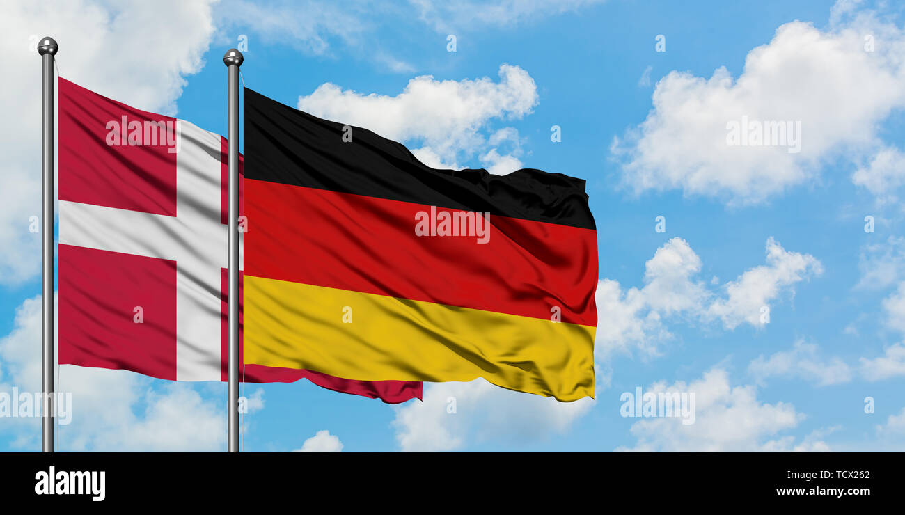 Denmark and Germany flag waving in the wind against white cloudy blue ...