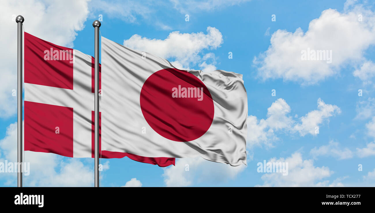 Denmark and Japan flag waving in the wind against white cloudy blue sky ...