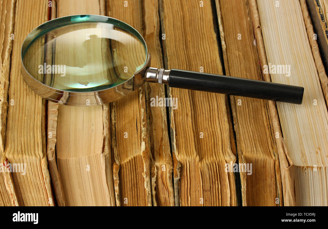 Magnifying glass over the stack of books Stock Photo - Alamy