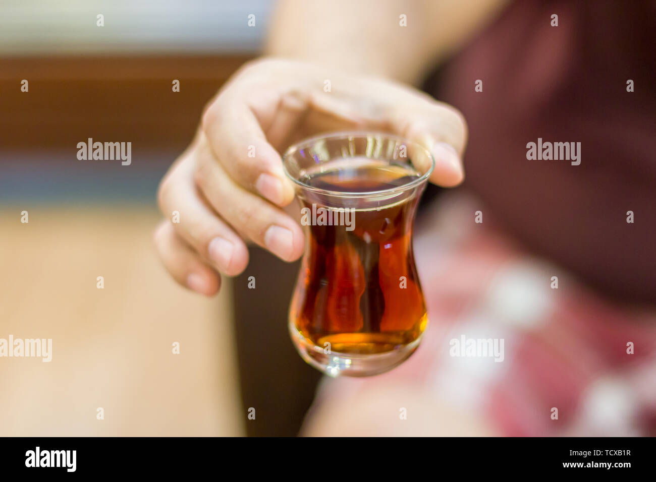 Turkish man holds out black Turkish tea in traditional glass Stock ...