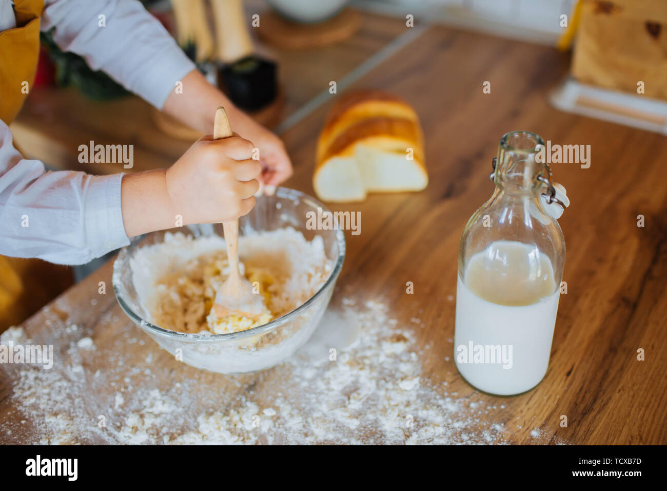Little girl helping mom bake a cake in the kitchen. Closeup with small ...