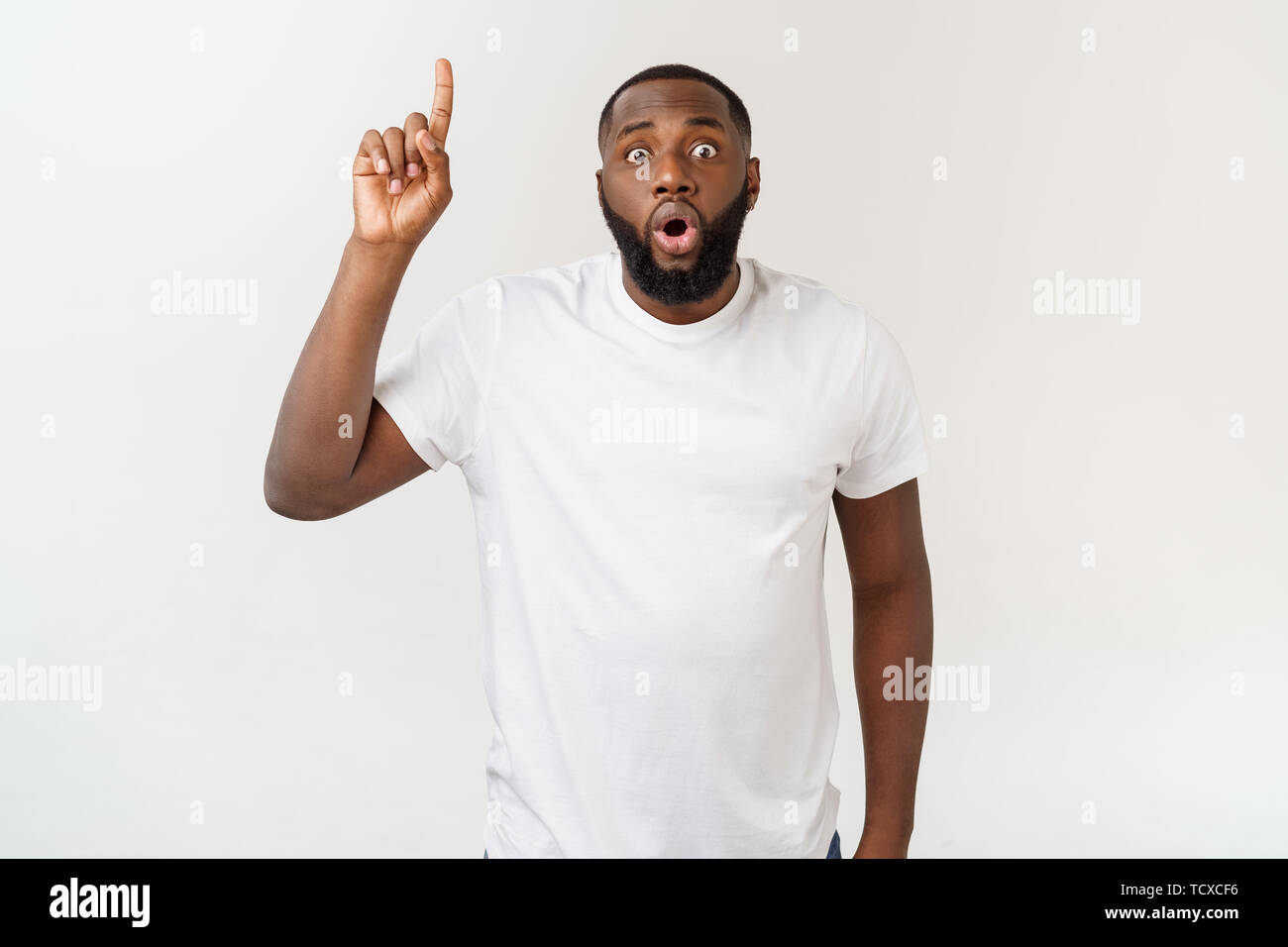 Young amazed African American pointing his finger at white background ...