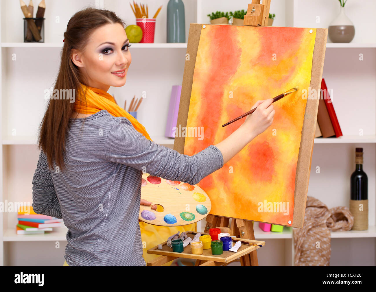 beautiful young woman painter at work, on room interior background ...