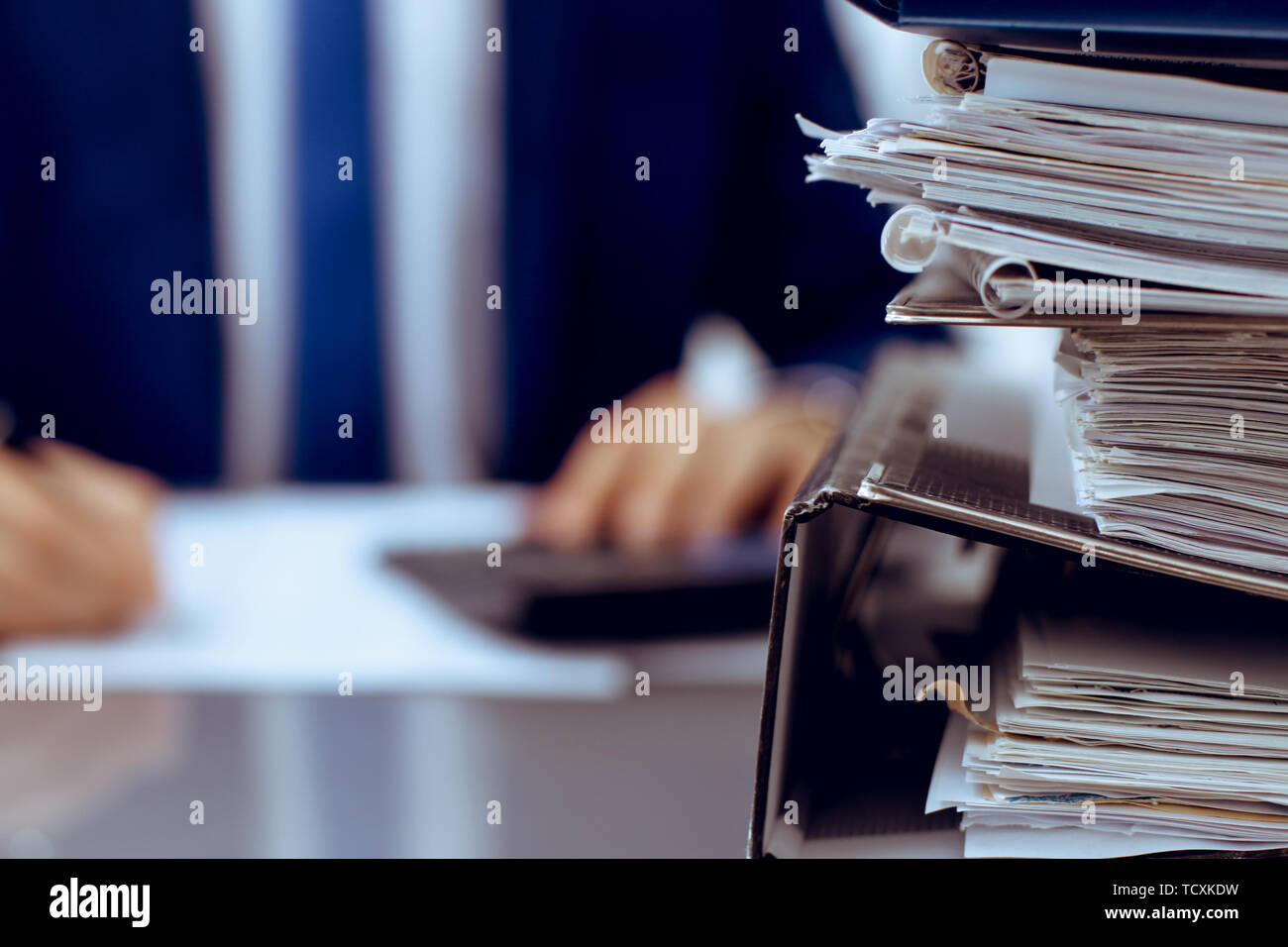 Binders with papers are waiting to be processed with businessman back ...