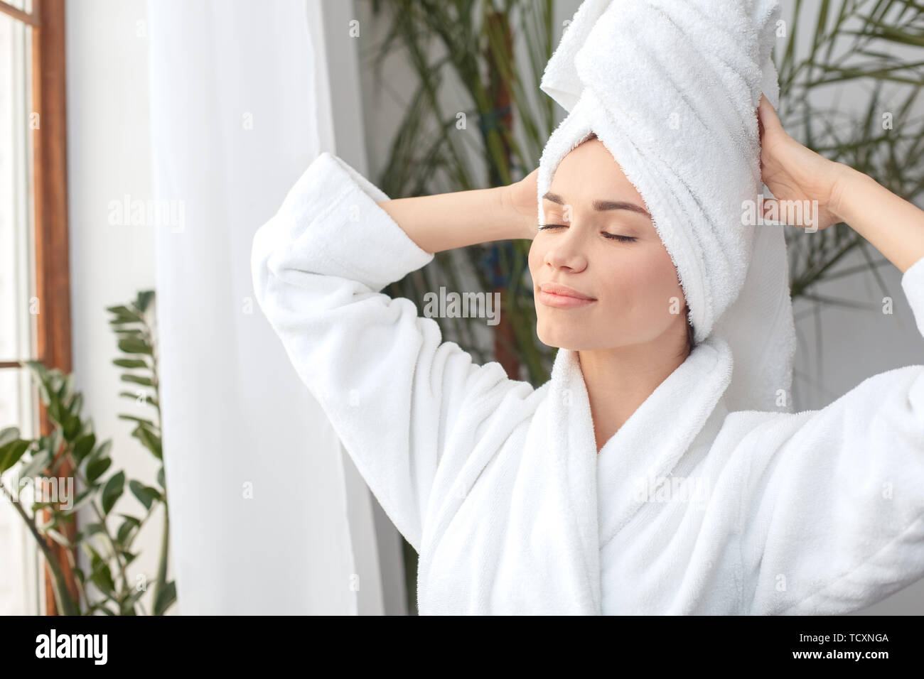 Young woman rest at home beauty care standing near window holding towel ...