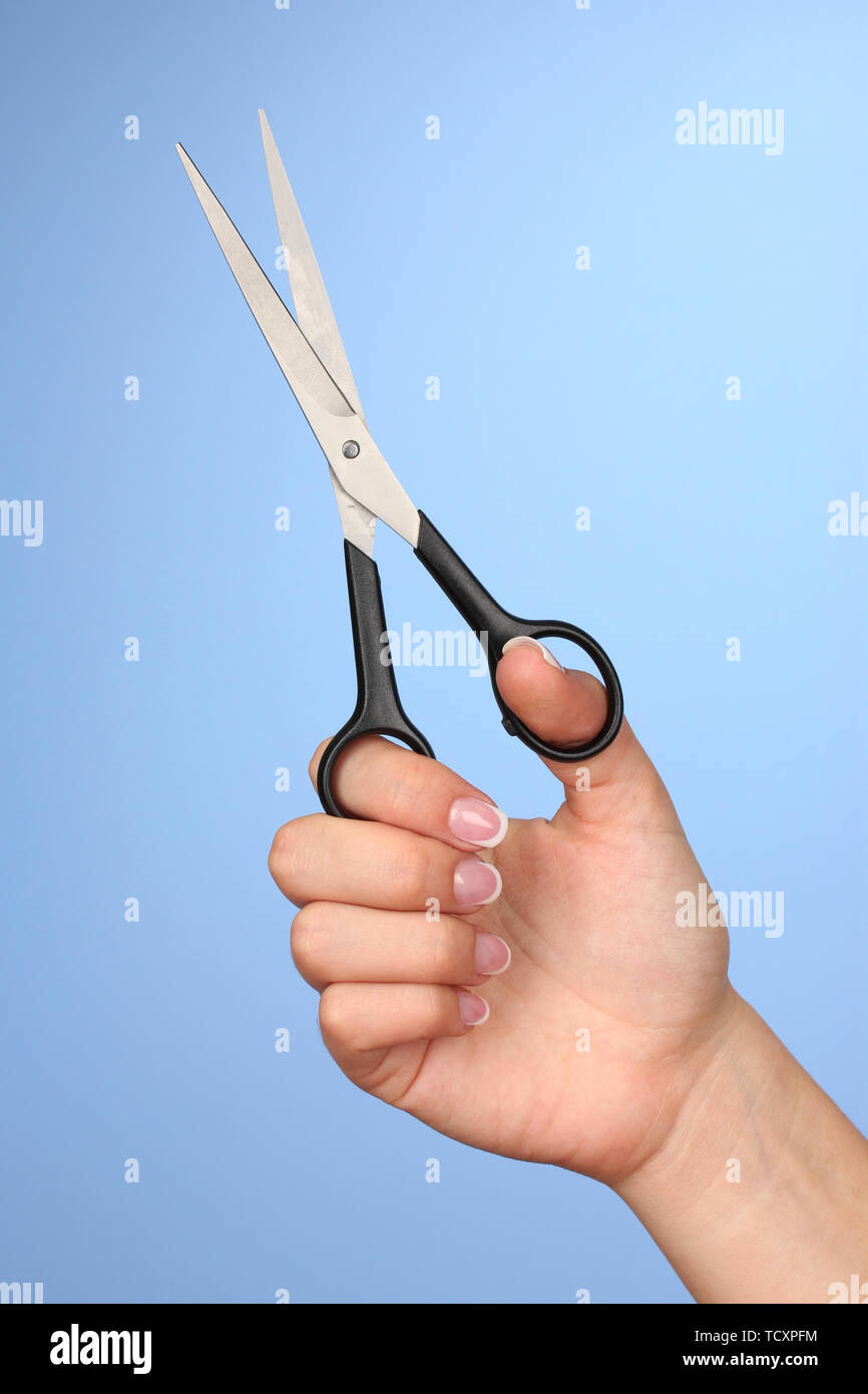 Female hand with scissors on color background Stock Photo - Alamy