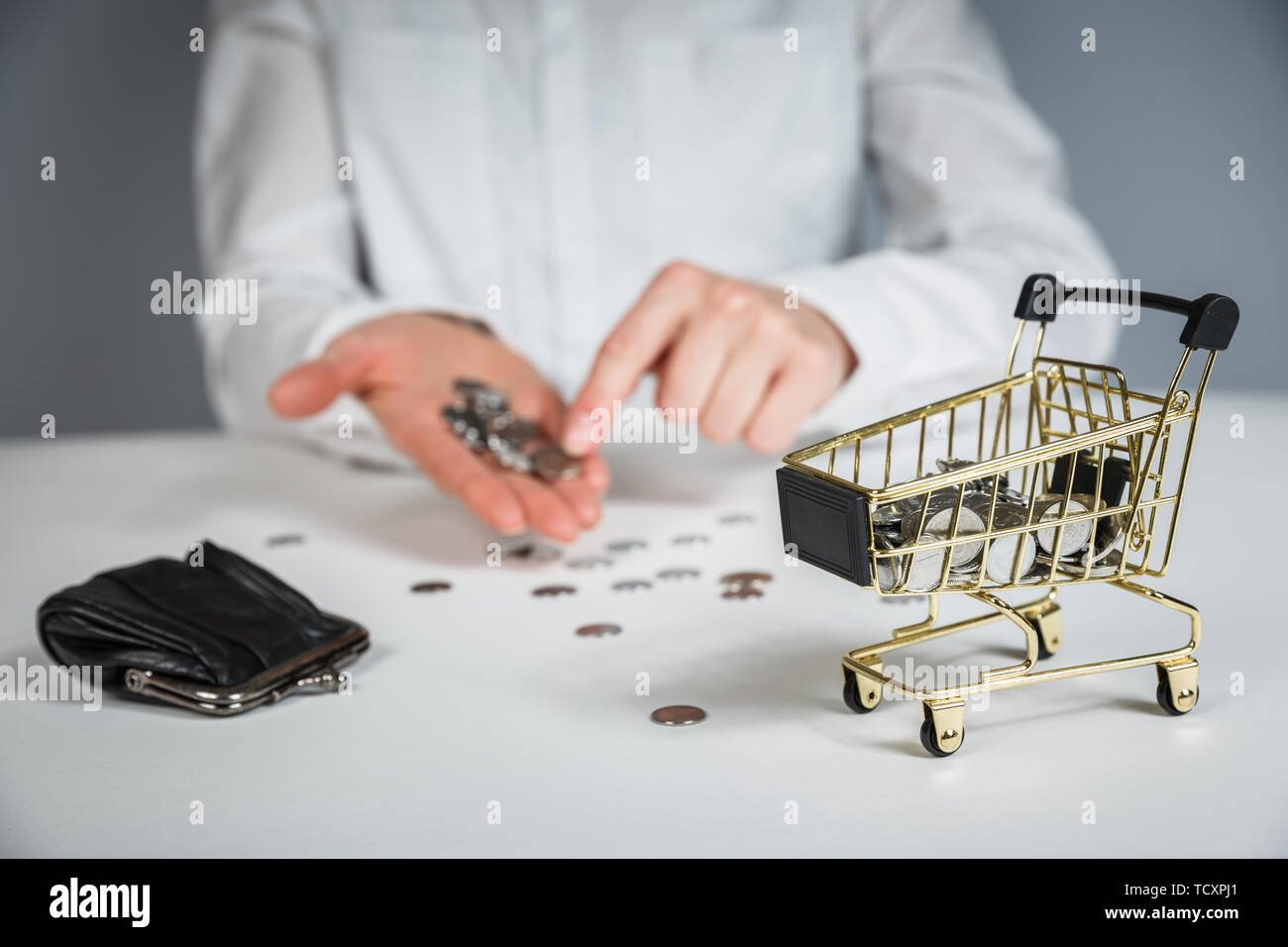 Hand holding a coin with pile of coin in the shopping cart on white and ...