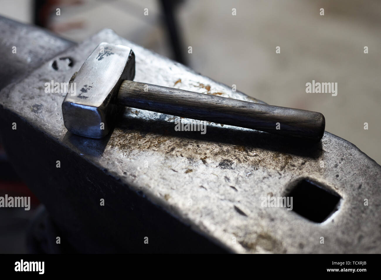 Close-up of heavy blacksmiths hammer placed on steel anvil with chipped ...