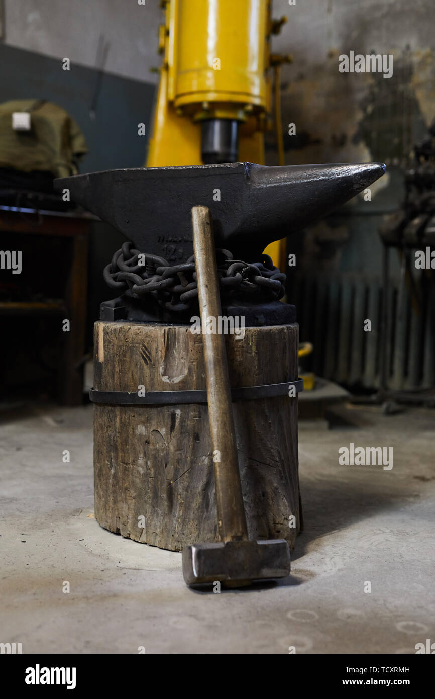 Heavy sledgehammer leaning on metal anvil fixed with steel chains on ...