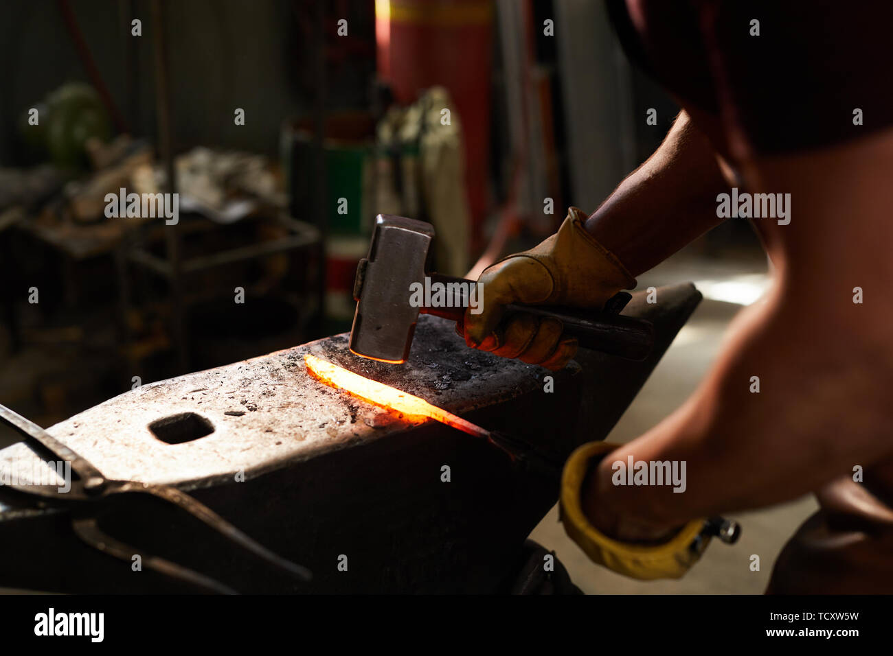 Close-up of unrecognizable blacksmith standing at steel anvil and ...