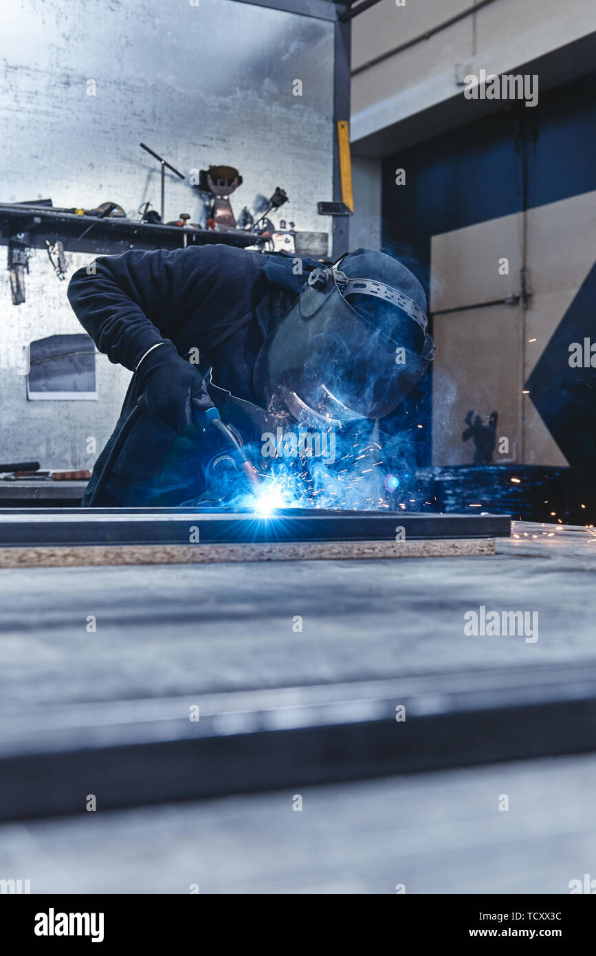 Industrial worker wearing helmet and gloves welding steel construction ...